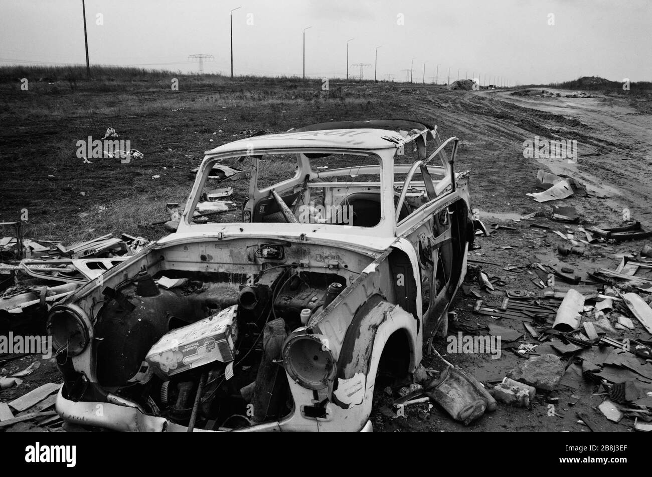 A wrecked shell of an East German Trabant motor car near a section of ...