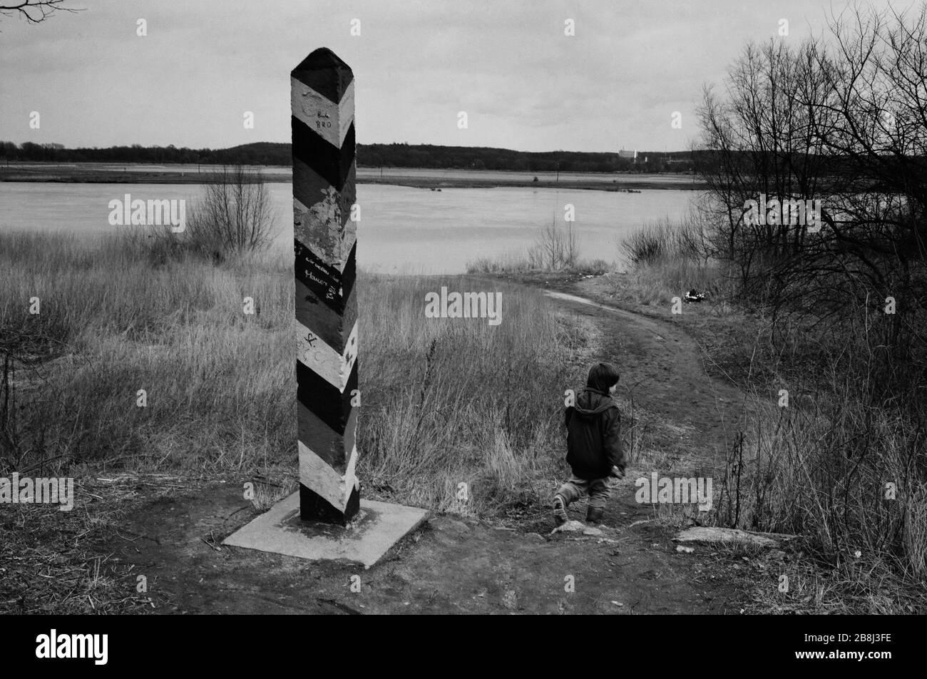A boy walking past a pillar marking the border between the former East ...