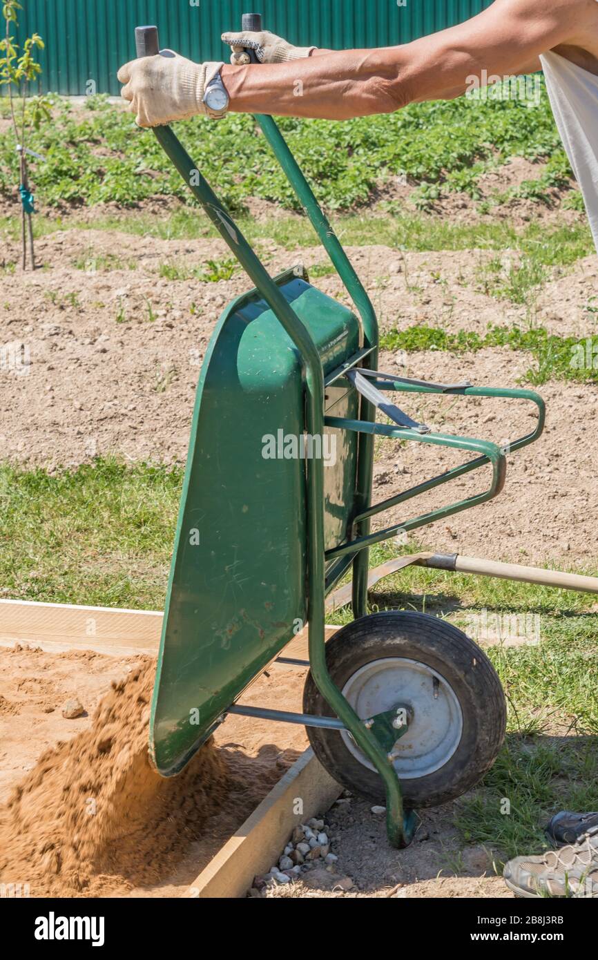 man holding wheelbarrow for transporting sand Stock Photo - Alamy