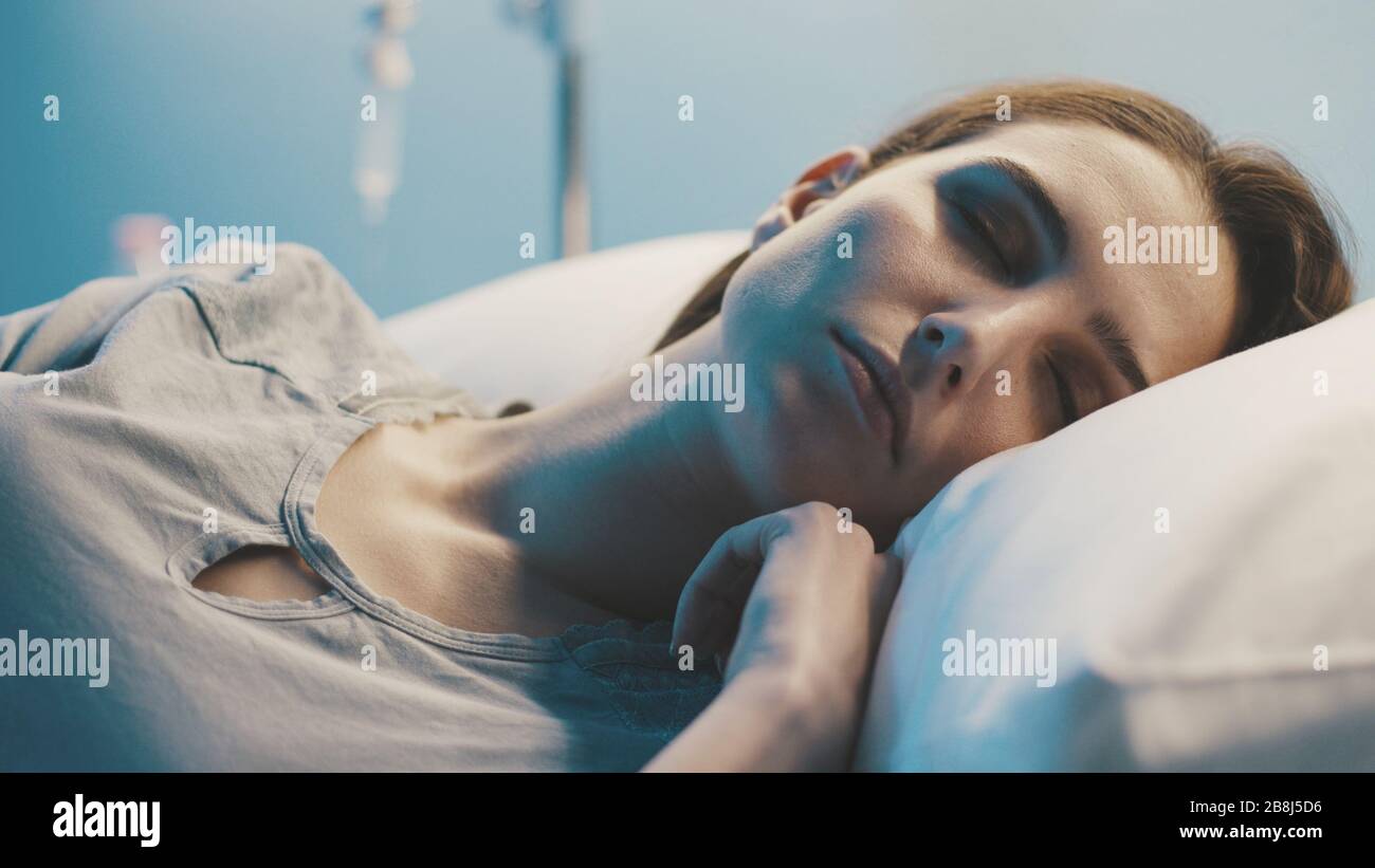 Young female patient lying in a hospital bed at night and sleeping ...