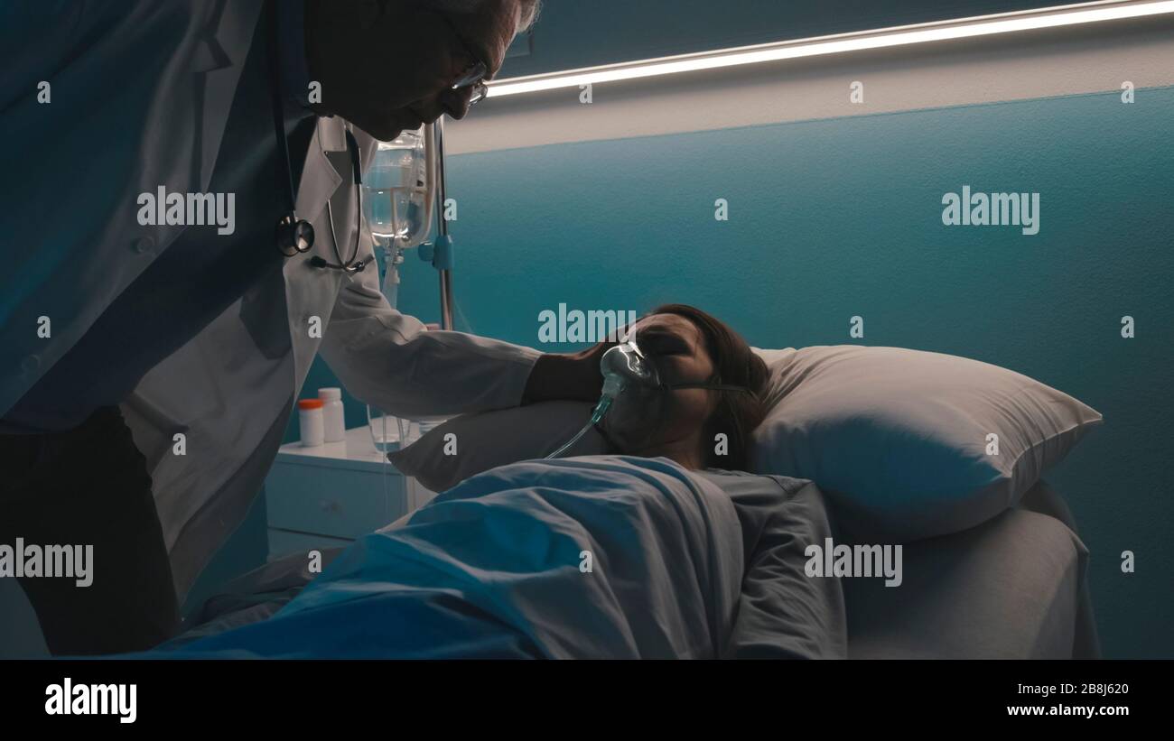 Hospitalized patient lying in a hospital bed at night, a doctor is ...