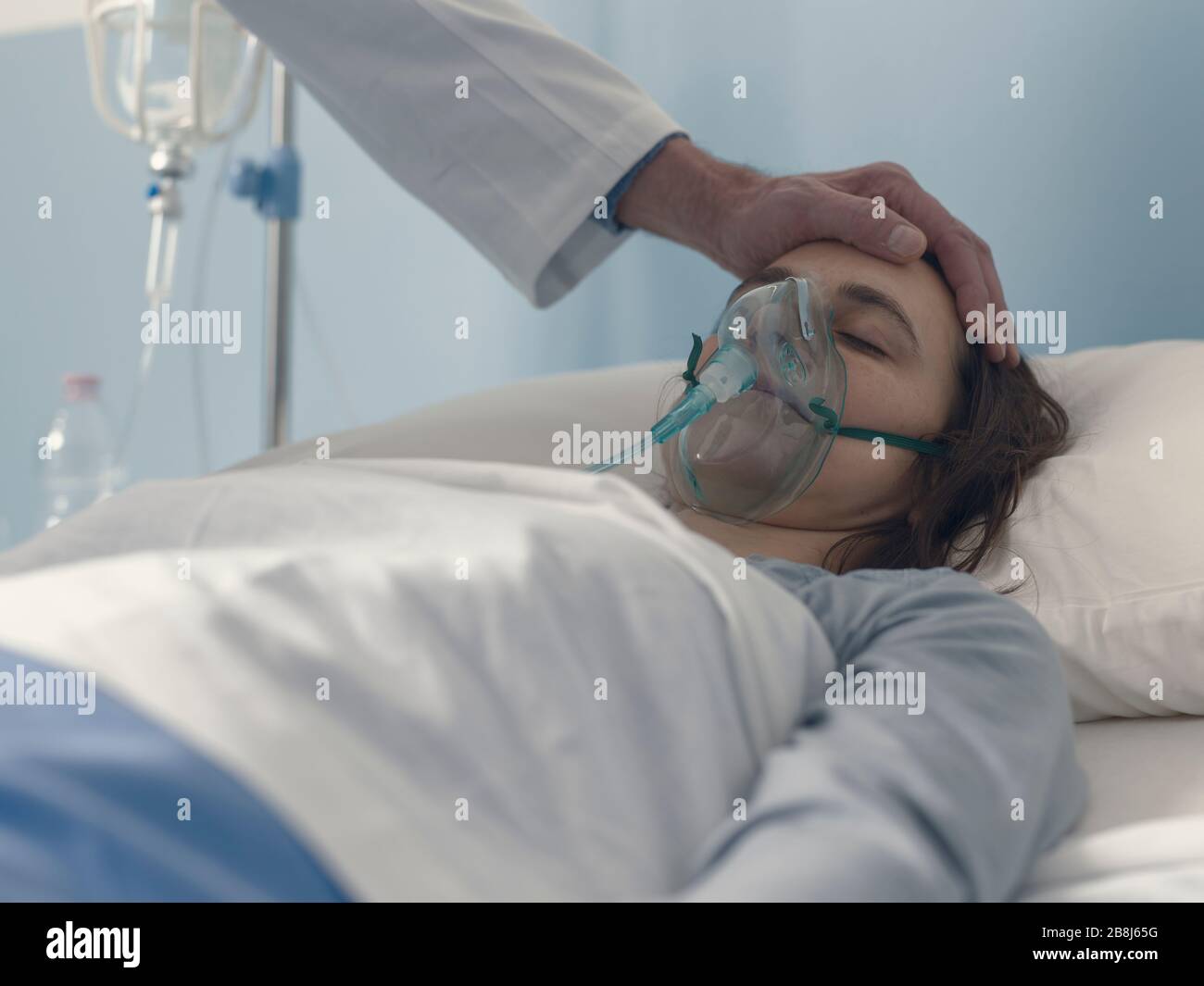 Professional doctor assisting a young patient lying in bed at the ...