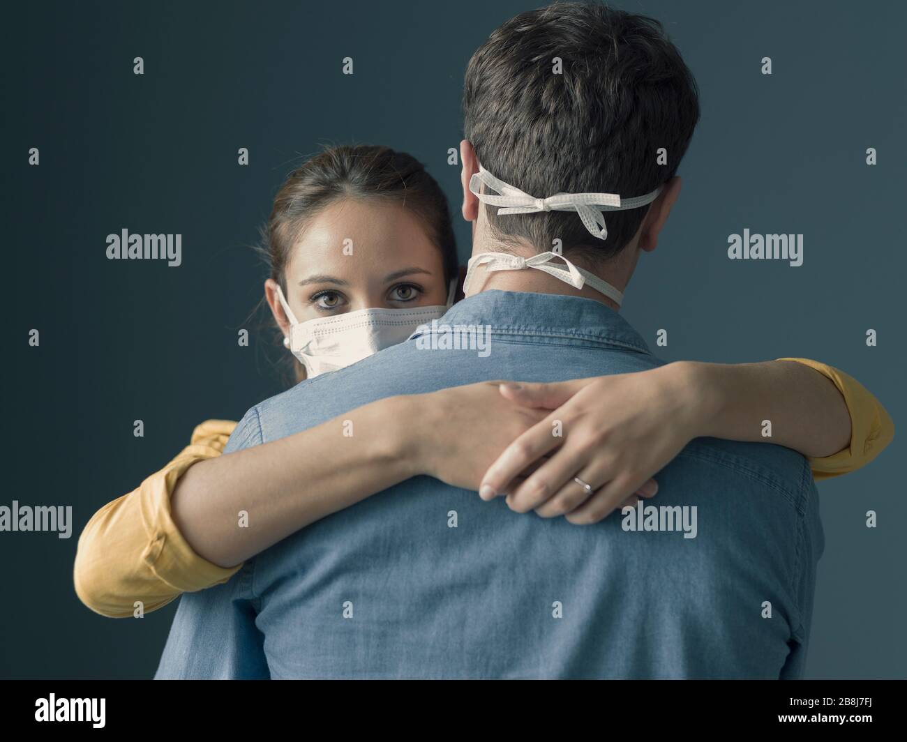 Young millennials couple hugging and wearing a protective face mask ...