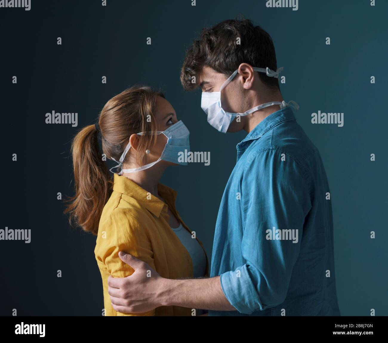 Young loving couple wearing face masks, hugging and staring at each ...