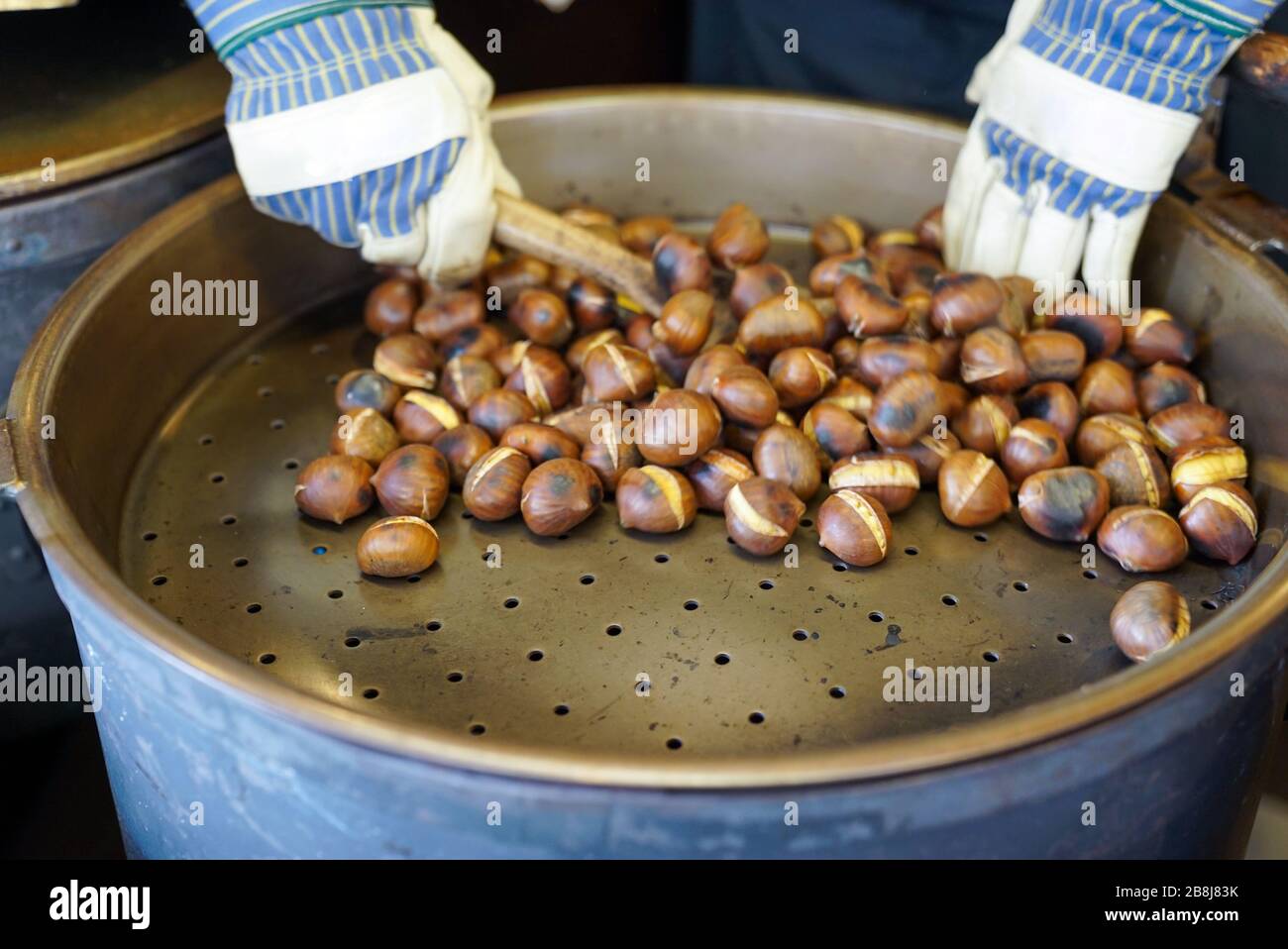 View of male hands stirring and roasting delicious organic chestnuts on ...