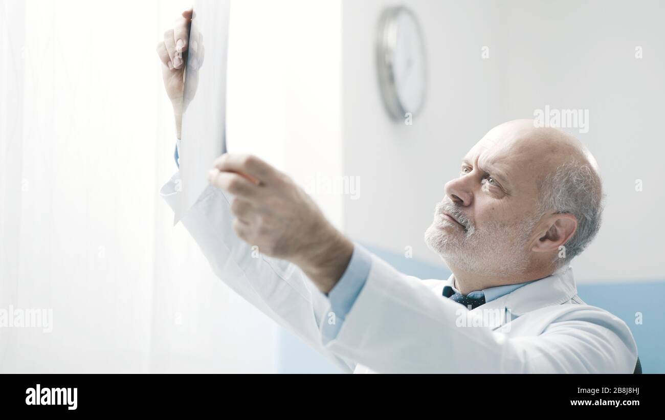 Professional senior doctor checking a patient's radiography at the ...