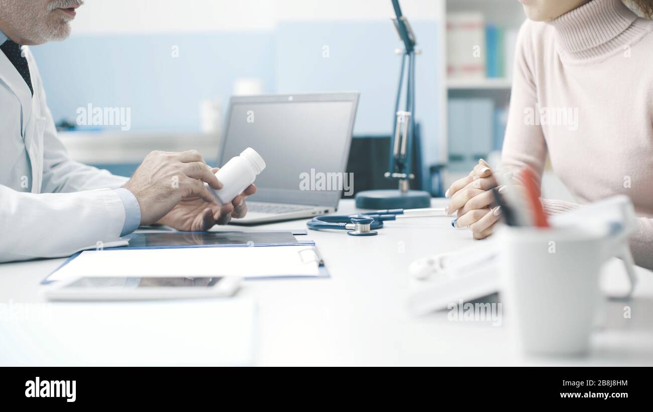 Professional senior doctor meeting a patient in the office and giving a ...