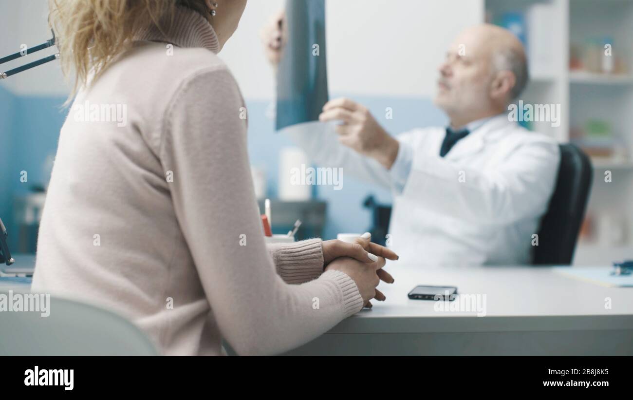Professional radiologist sitting at desk and checking a patient's x-ray ...