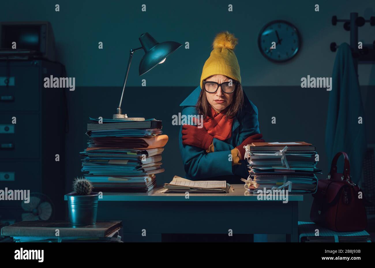 Sad businesswoman working late at night in the office and freezing, she ...