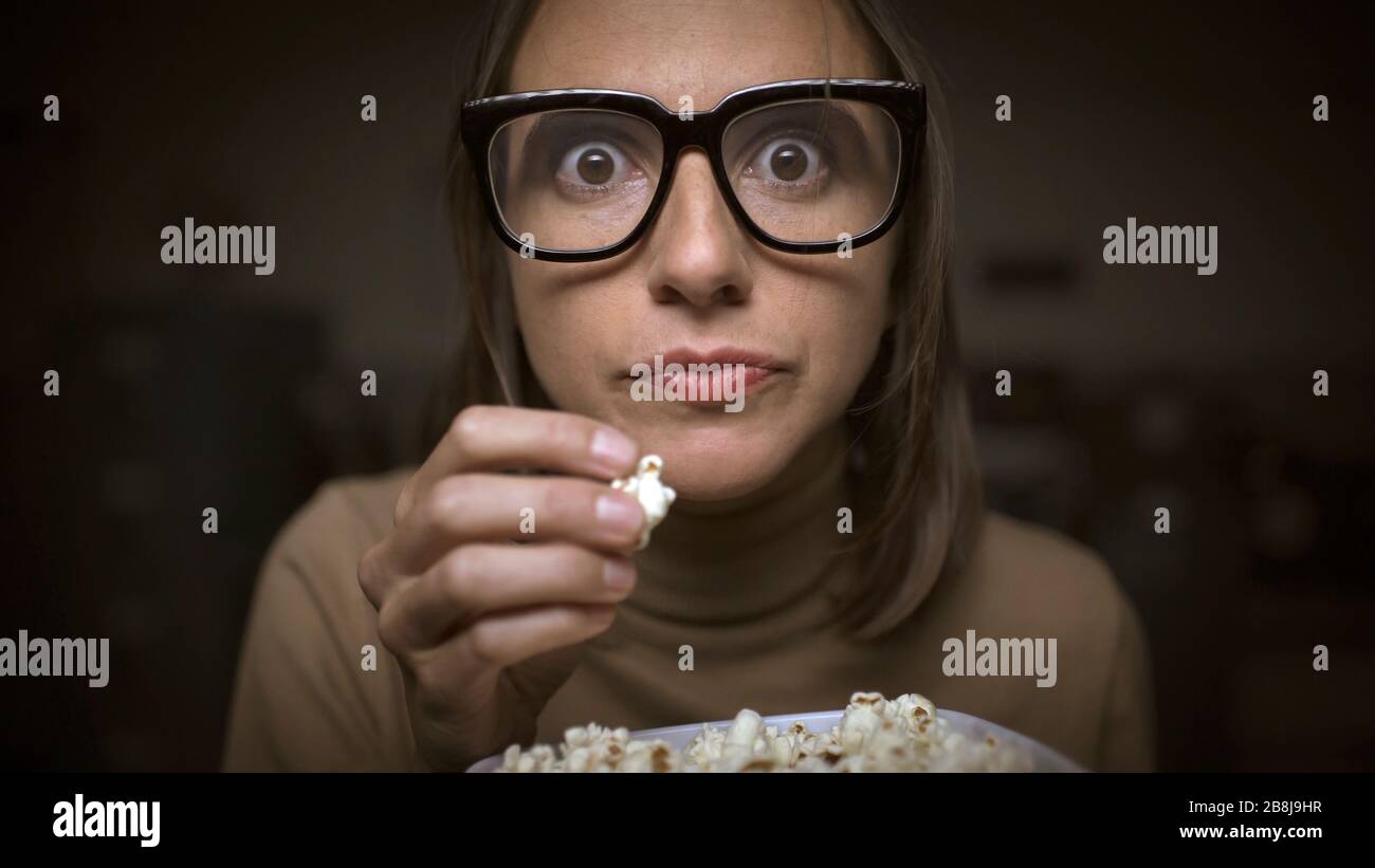 Woman watching movies and eating popcorn, she is addicted and glued to ...