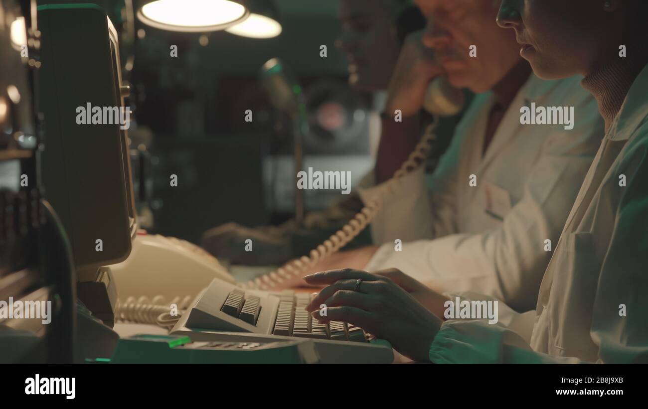 Team of scientists working in a vintage style control room, they are ...