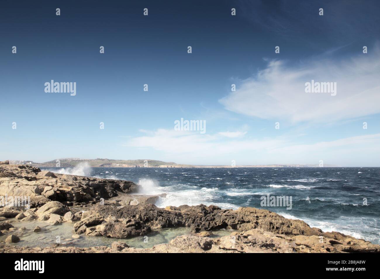 close up of a rocky beach in Qawra Point Beach in Malta on a cloudy day ...