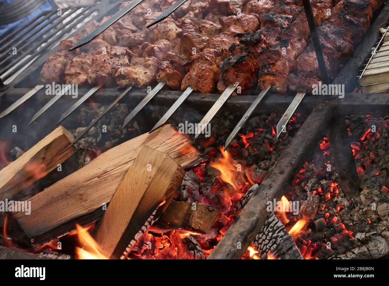 Pieces of meat are roasted on metal bars over hot charcoal, close-up ...