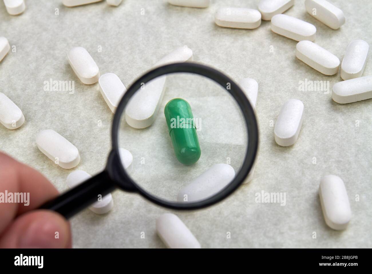 Zooming green capsule pill using magnifier Stock Photo - Alamy