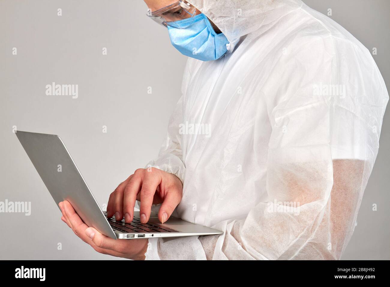 Man in white protective suit respirator mask using laptop pc Stock ...