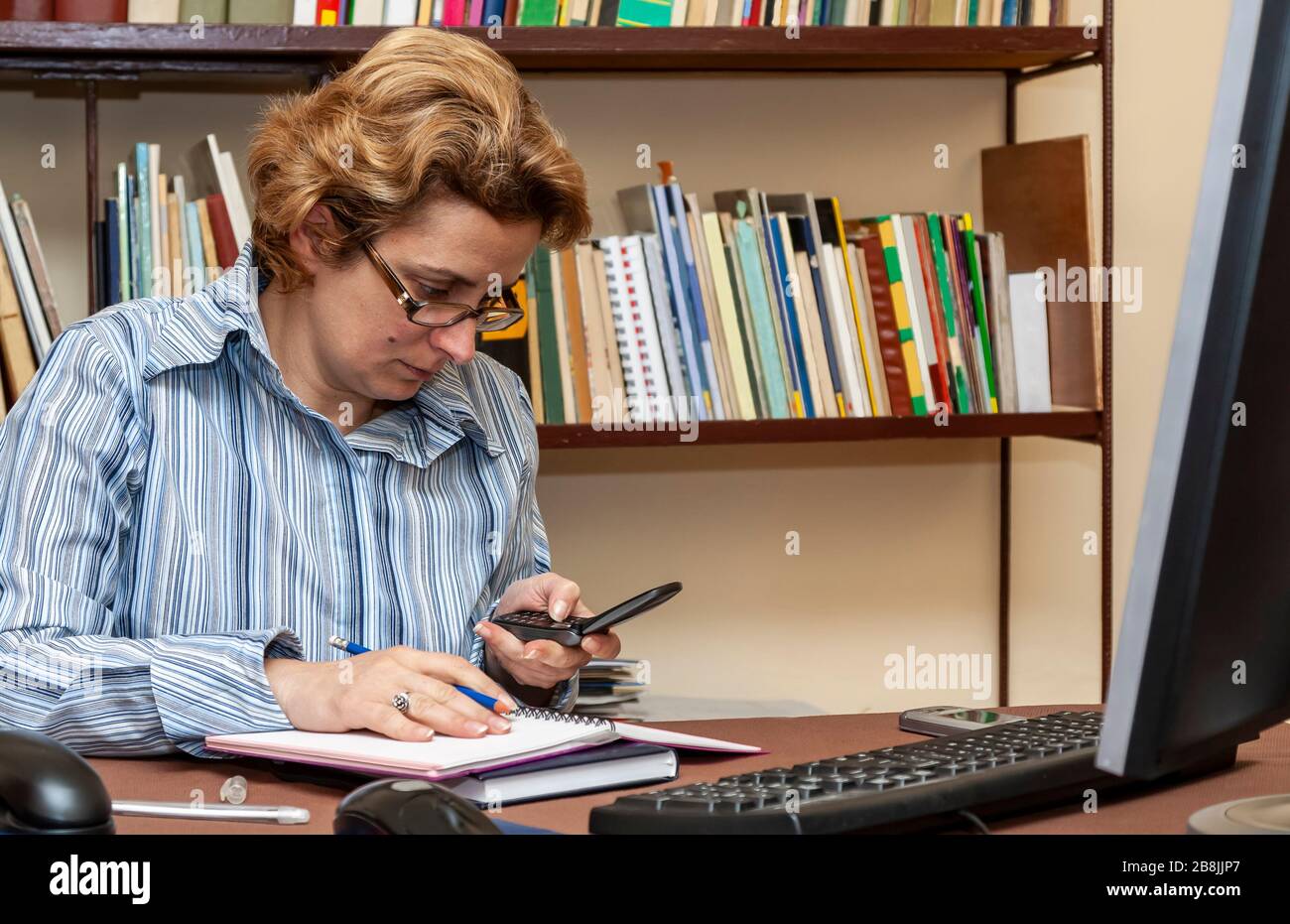 Image of a busy woman teleworking at her desk at the home. Working at ...