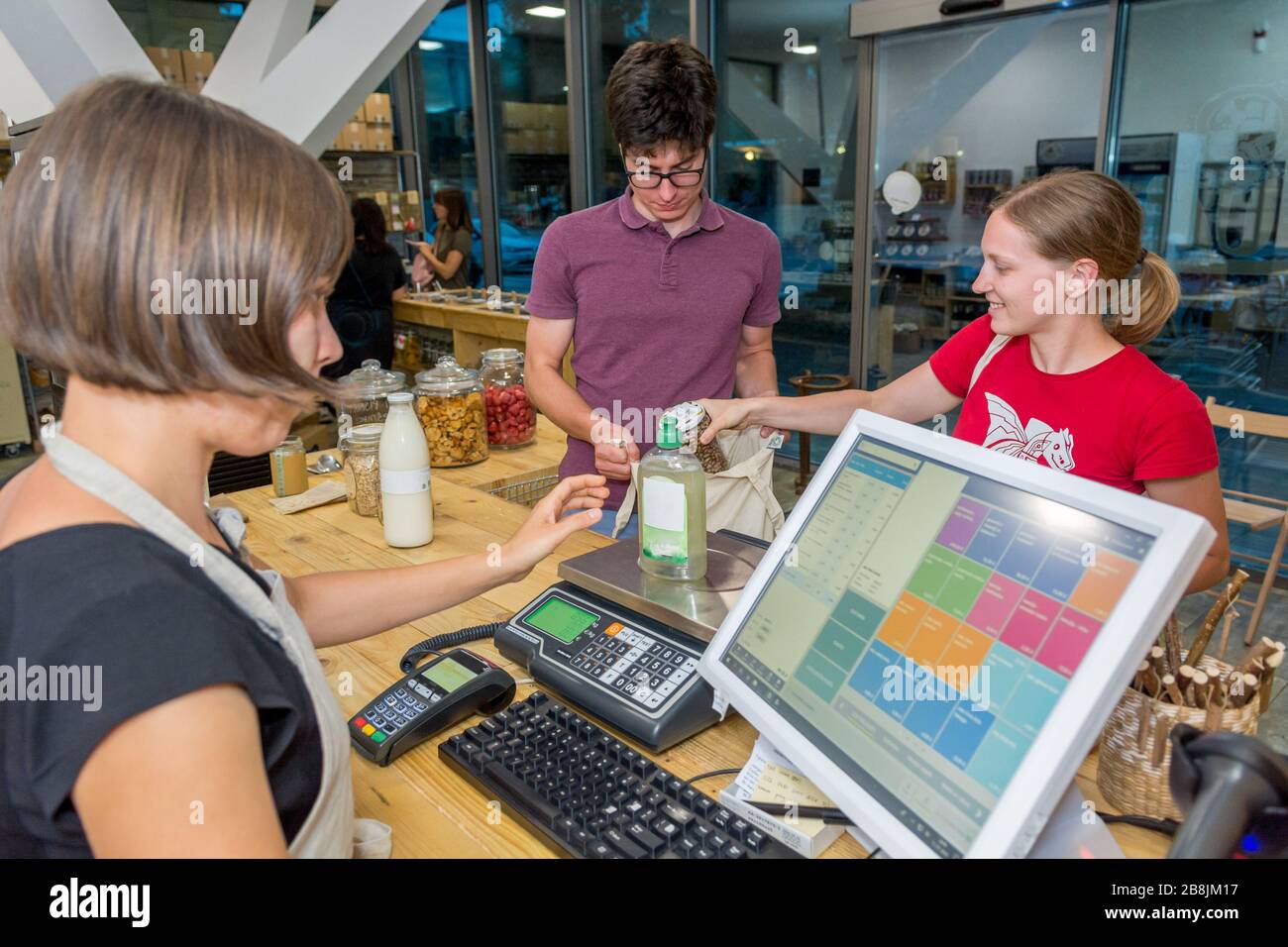 Female shop assistant serving a couple at a desk Stock Photo - Alamy