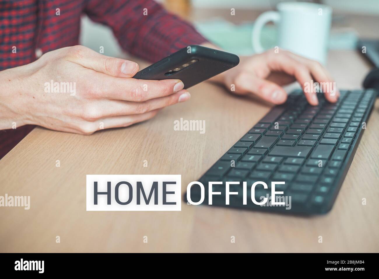 Young man is holding mobile phone in his hands, indoor at home office ...