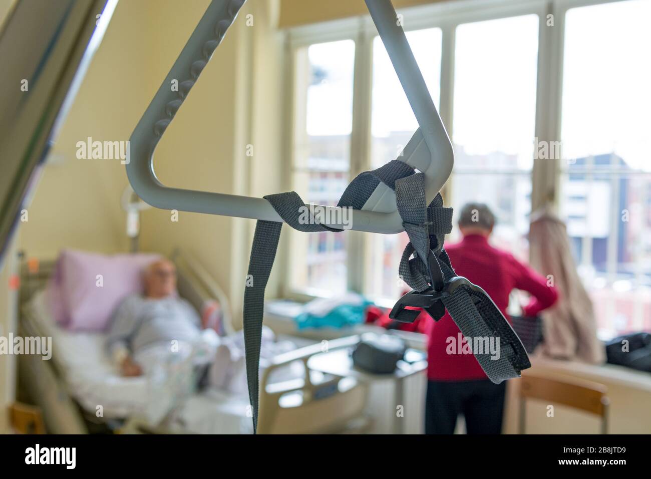 Hospital bed triangle with unrecognizable elderly couple in the ...
