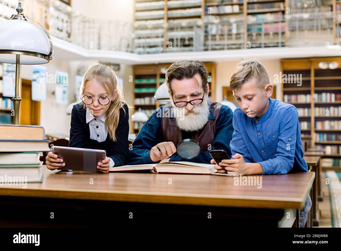 Family, education, digital technologies vs book. Elderly man reading ...