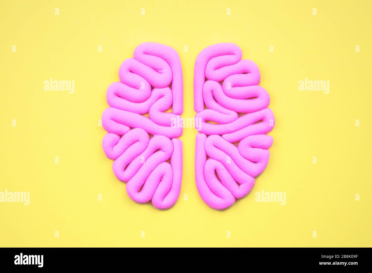 Pink model of human brain from above on yellow background, flat lay ...