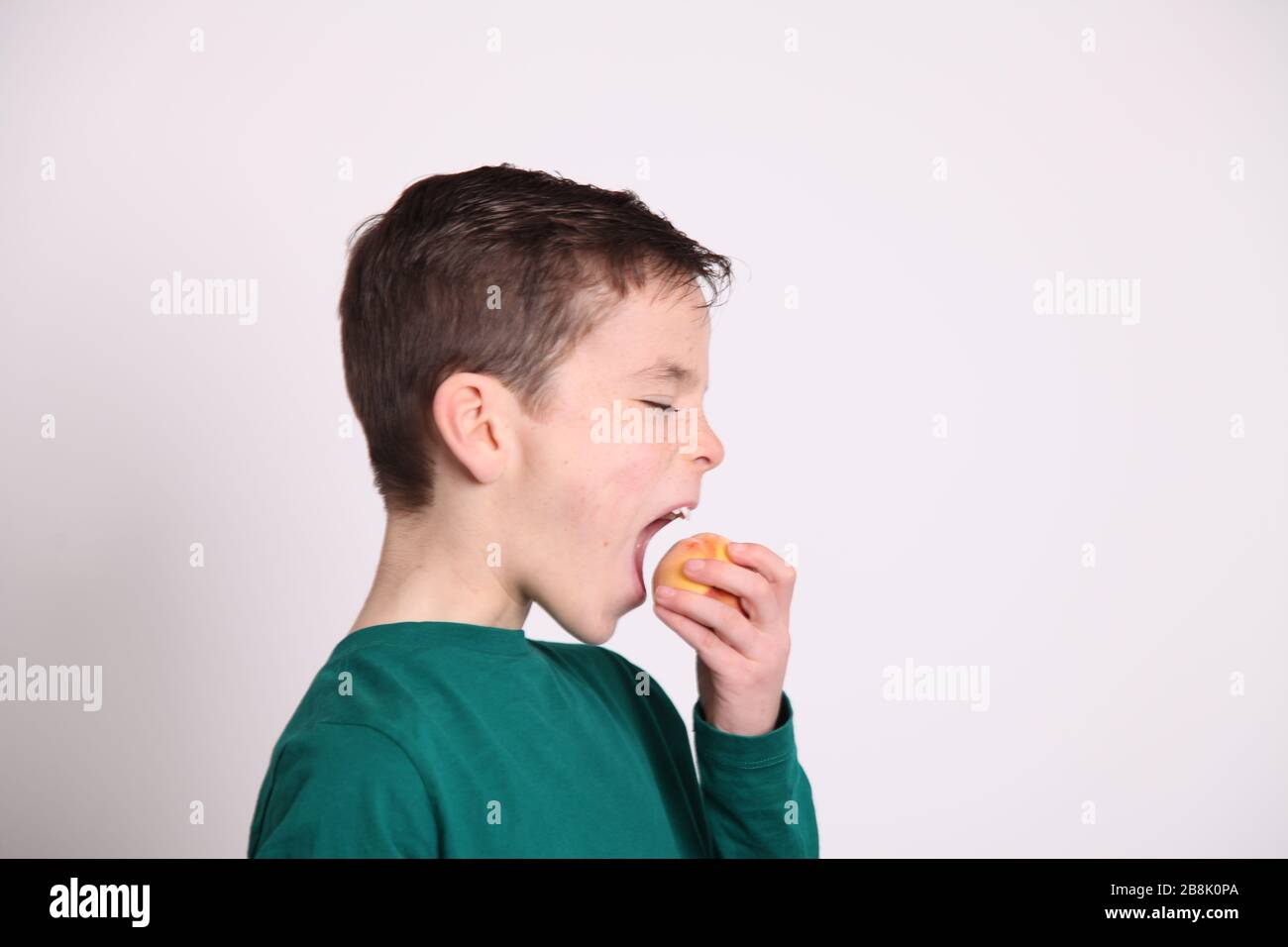 Boy biting peach hi-res stock photography and images - Alamy