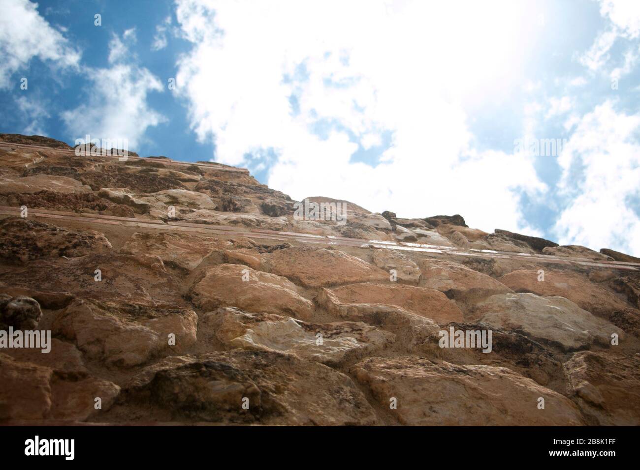 backlit stone wall texture with sun and cloudy sky background Stock ...