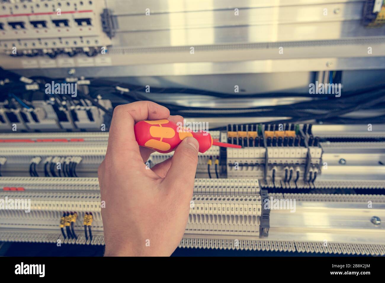 Electrical engineer checking electric cubicle and fixing connector ...