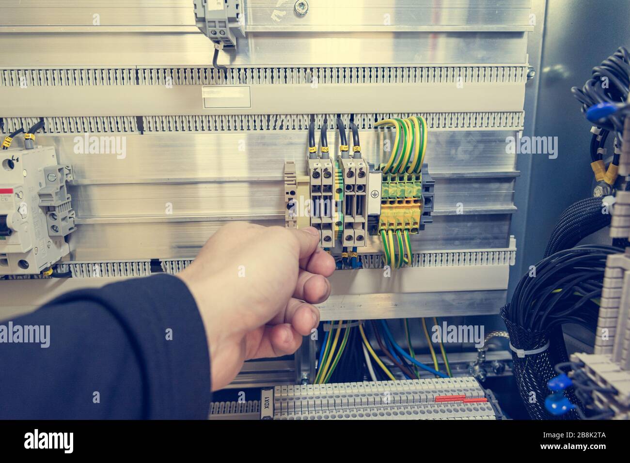 Finger pointing at numbering of connector strip inside electric cubicle ...