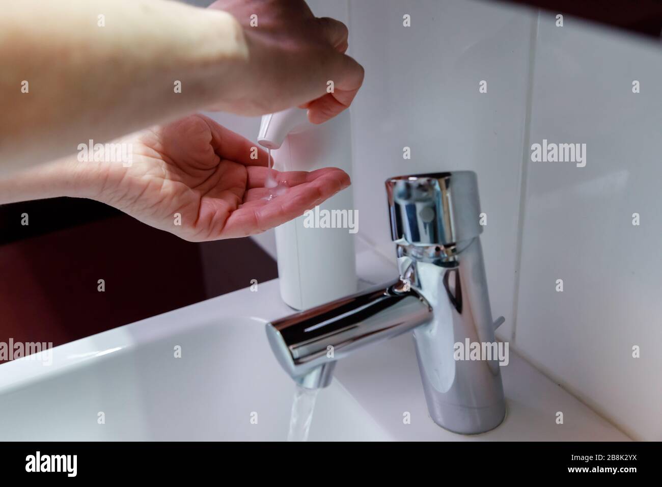 A woman uses anti bacterial rinsing soap to clean her hands to prevent ...