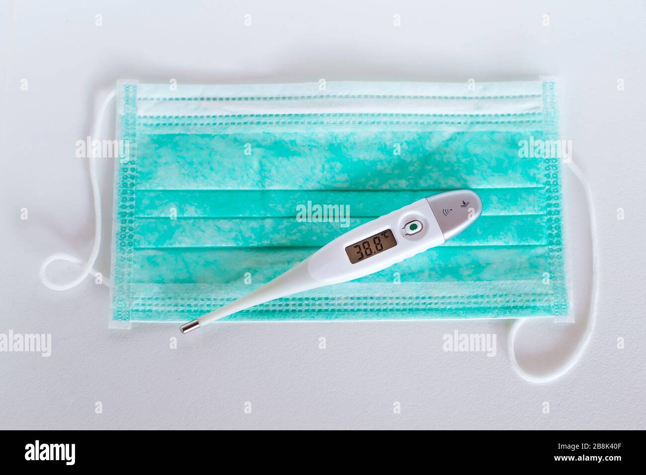 Surgical ear-loop mask and thermometer on the table Stock Photo - Alamy