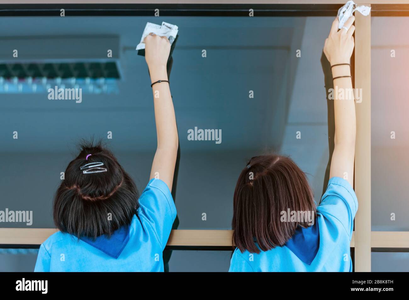 Back view of female students are helping to wipe the glass with wet ...