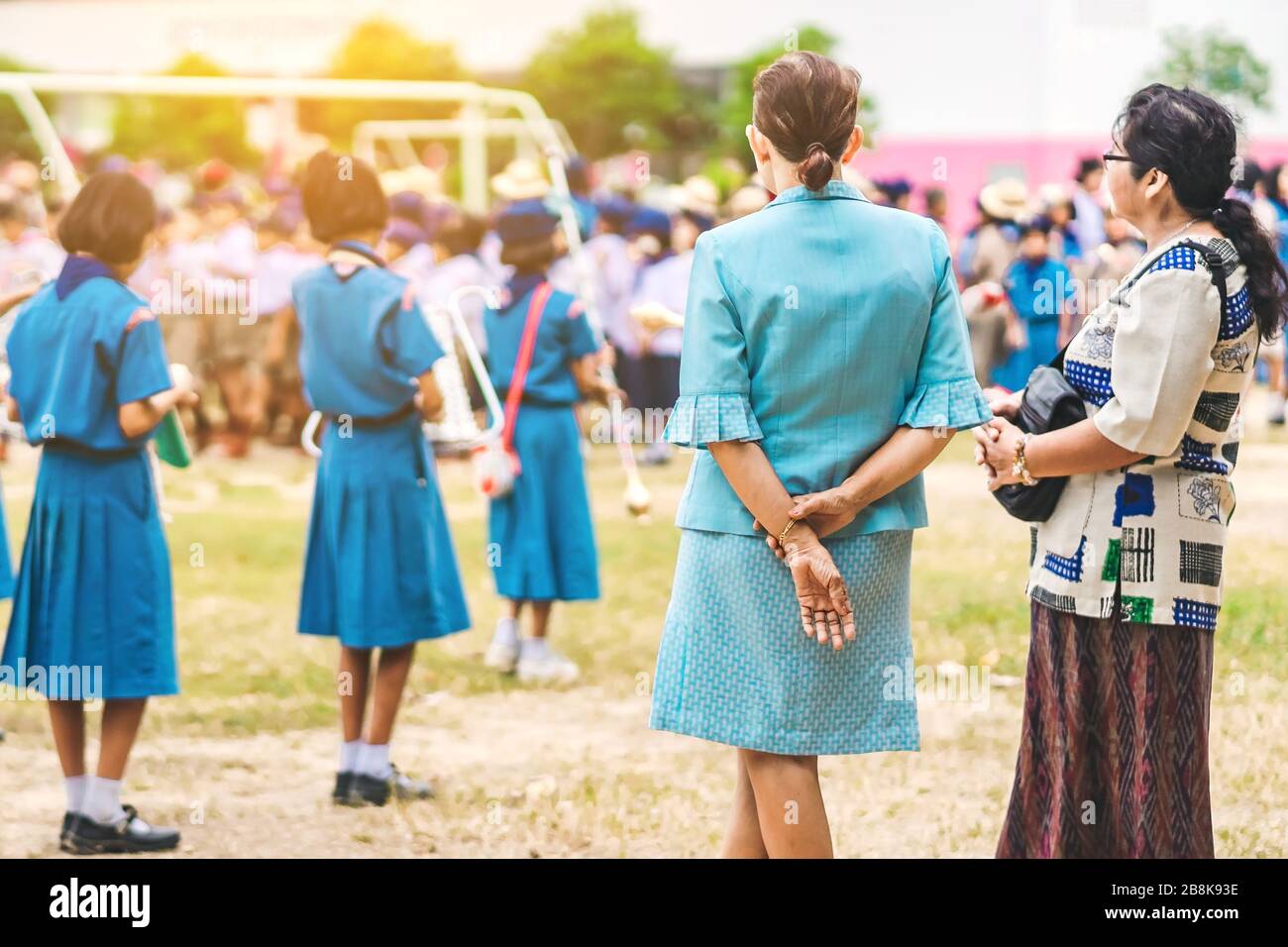 Asian female teacher stand to control the students playing music while ...