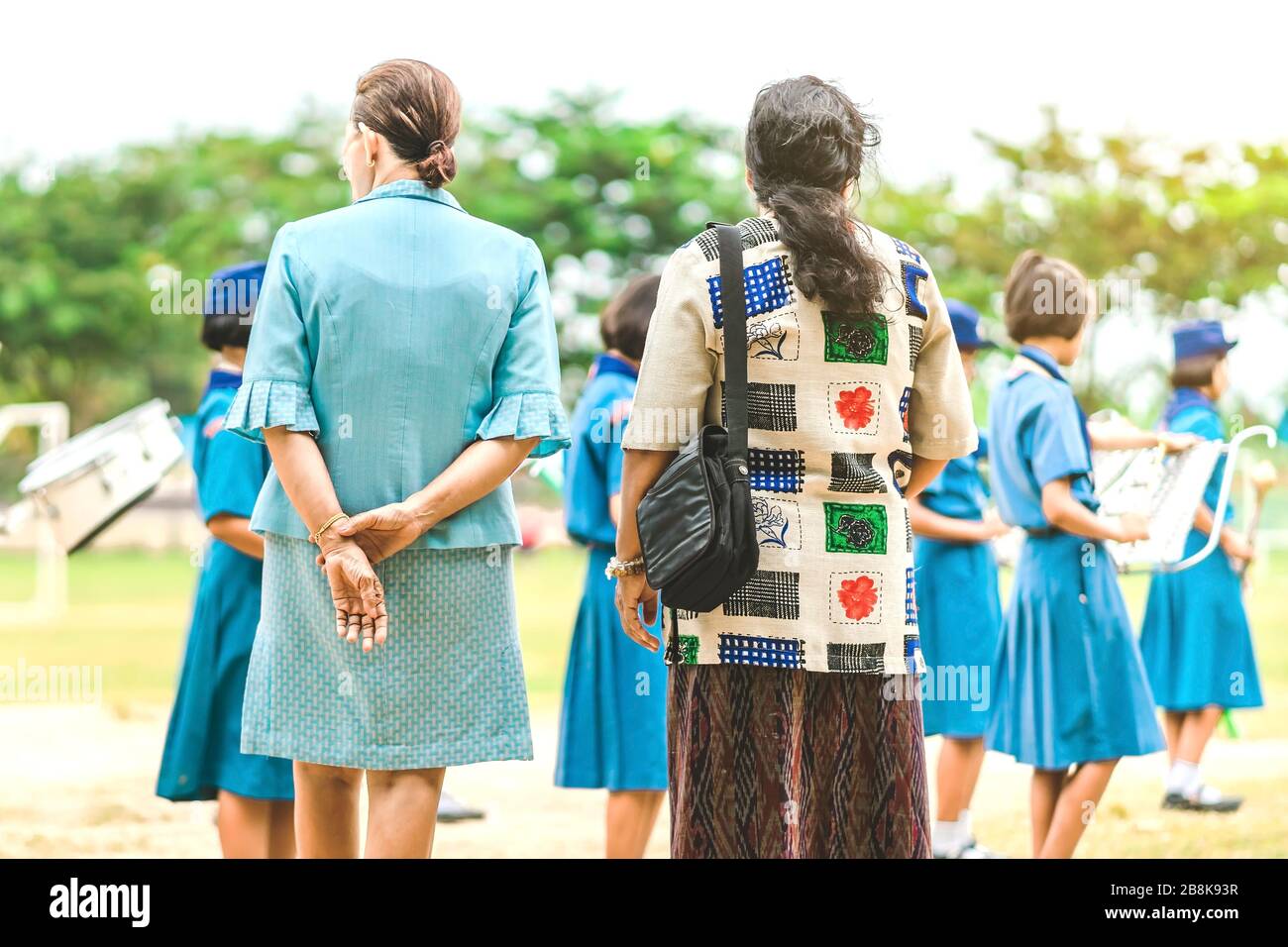 Asian female teacher stand to control the students playing music while ...