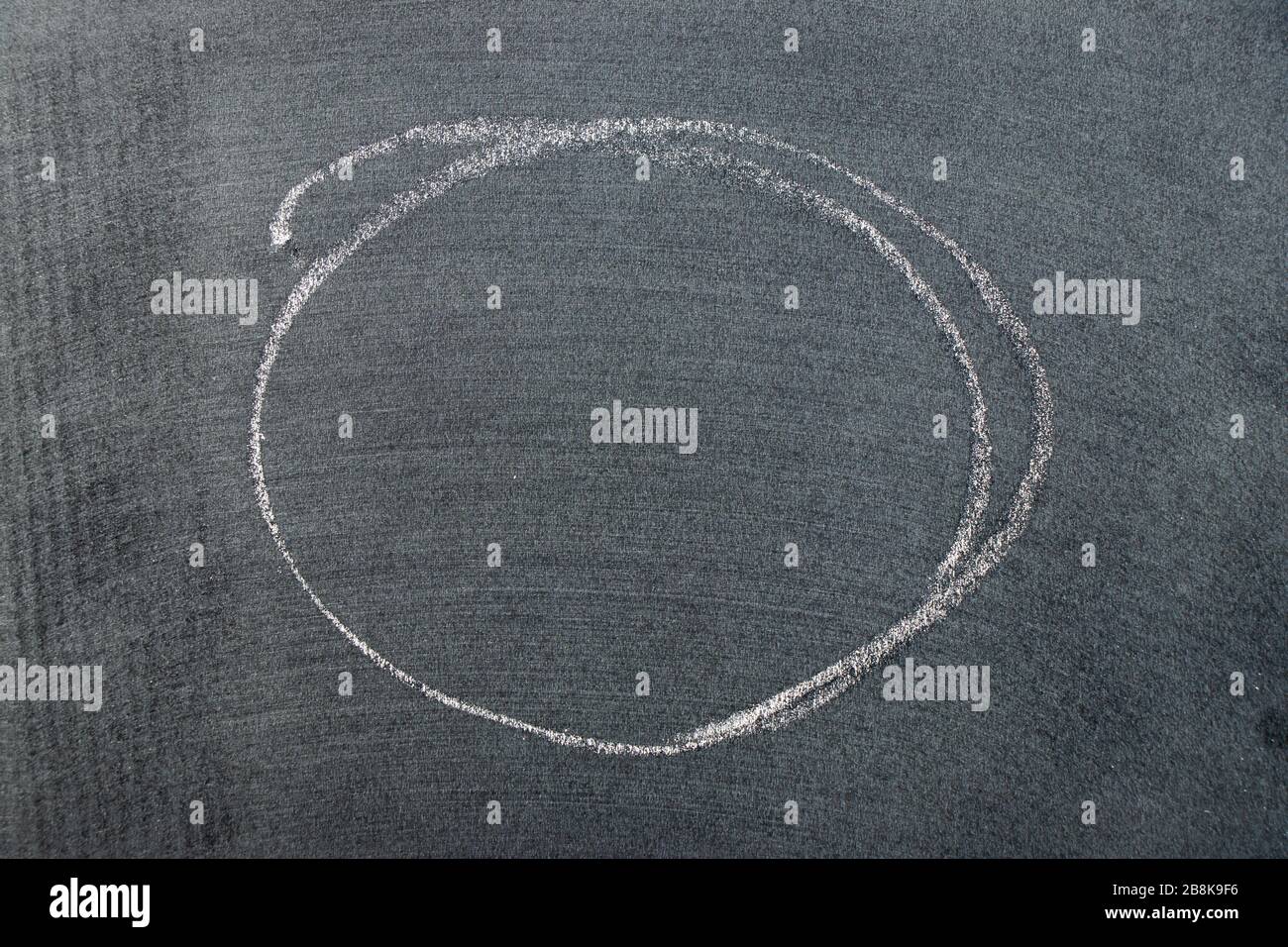 White color chalk hand drawing in circle or oval shape on black board ...