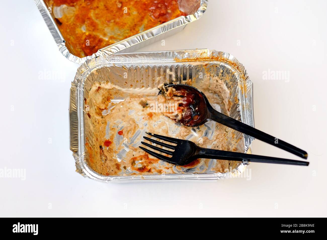 dirty empty aluminum container with black plastic spoon and fork top ...