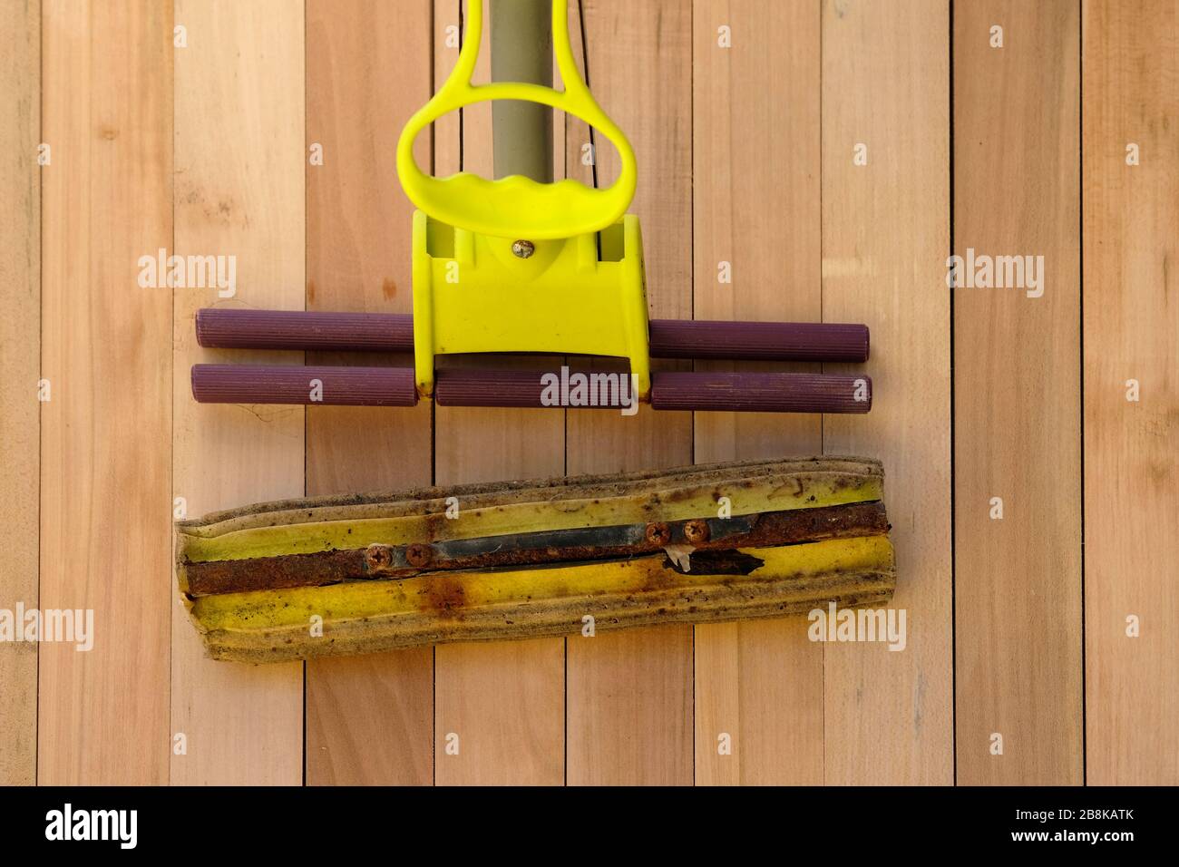 Old broken squeezed squeegee with a dirty soft sponge. A mop on the ...