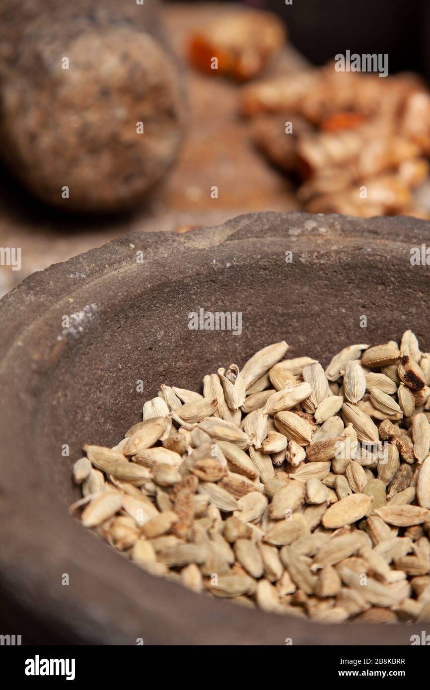 Display of cardamon pods or seeds, with grey stone mortar and pestle ...