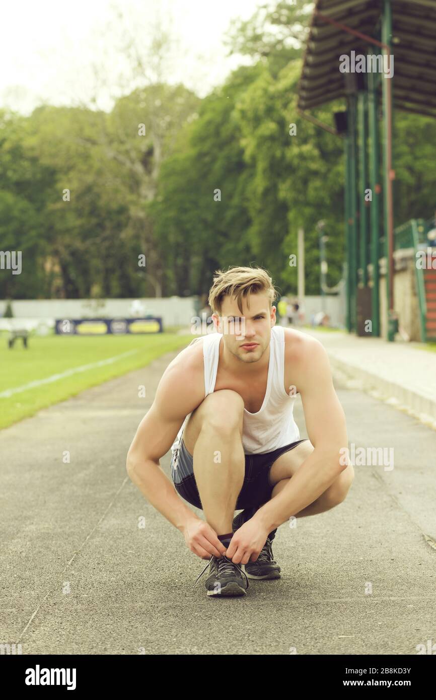 Sportsman ties his trainers sitting and getting ready to run, on ...