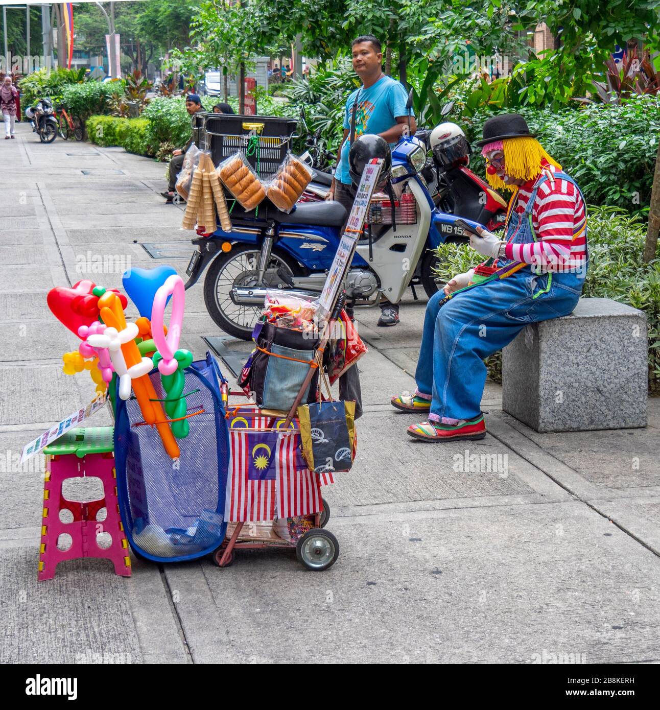 Street vendor and a busker in clown costume who twists balloons into ...