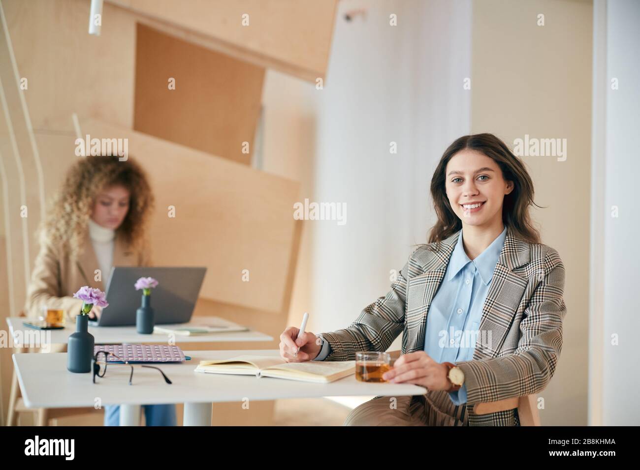 Portrait of smiling female student smiling at camera while studying in ...