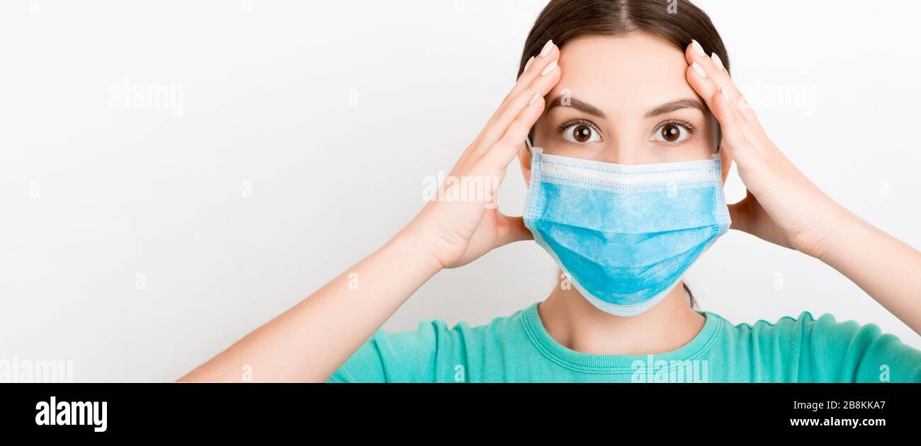 Portrait of young shocked woman wearing medical mask at white ...