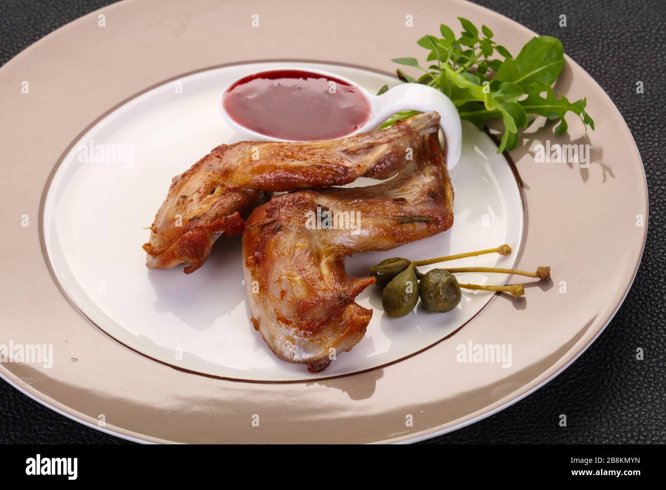 Roasted rabbit legs with cowberry sauce Stock Photo - Alamy