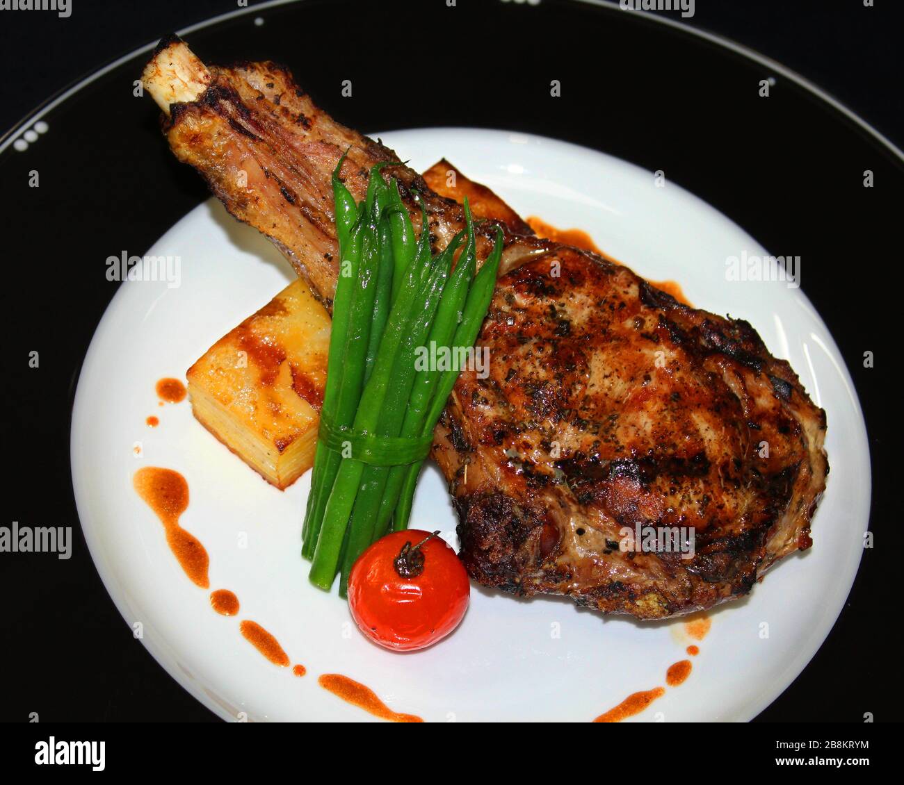 grilled angus beef rib with potato, green beans and tomato in a white ...