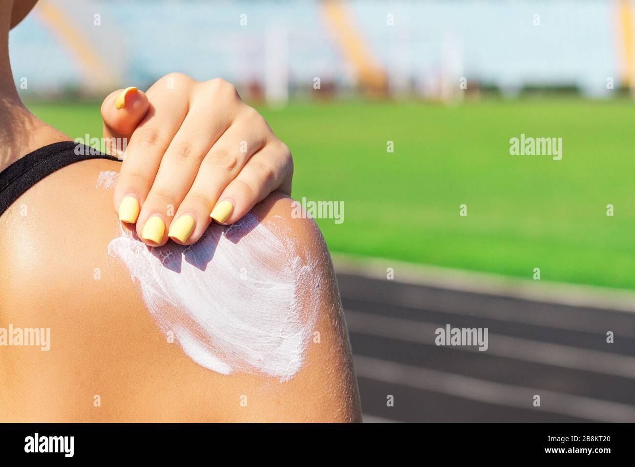 Fitness woman is applying sunscreen on her shoulder before training at ...