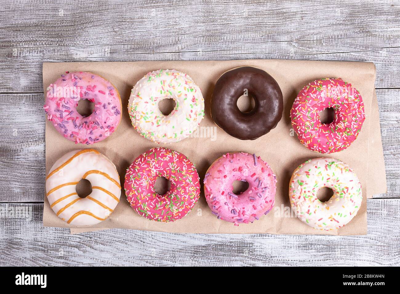 Eight traditional doughnuts with multicolored glaze neatly laid out on ...