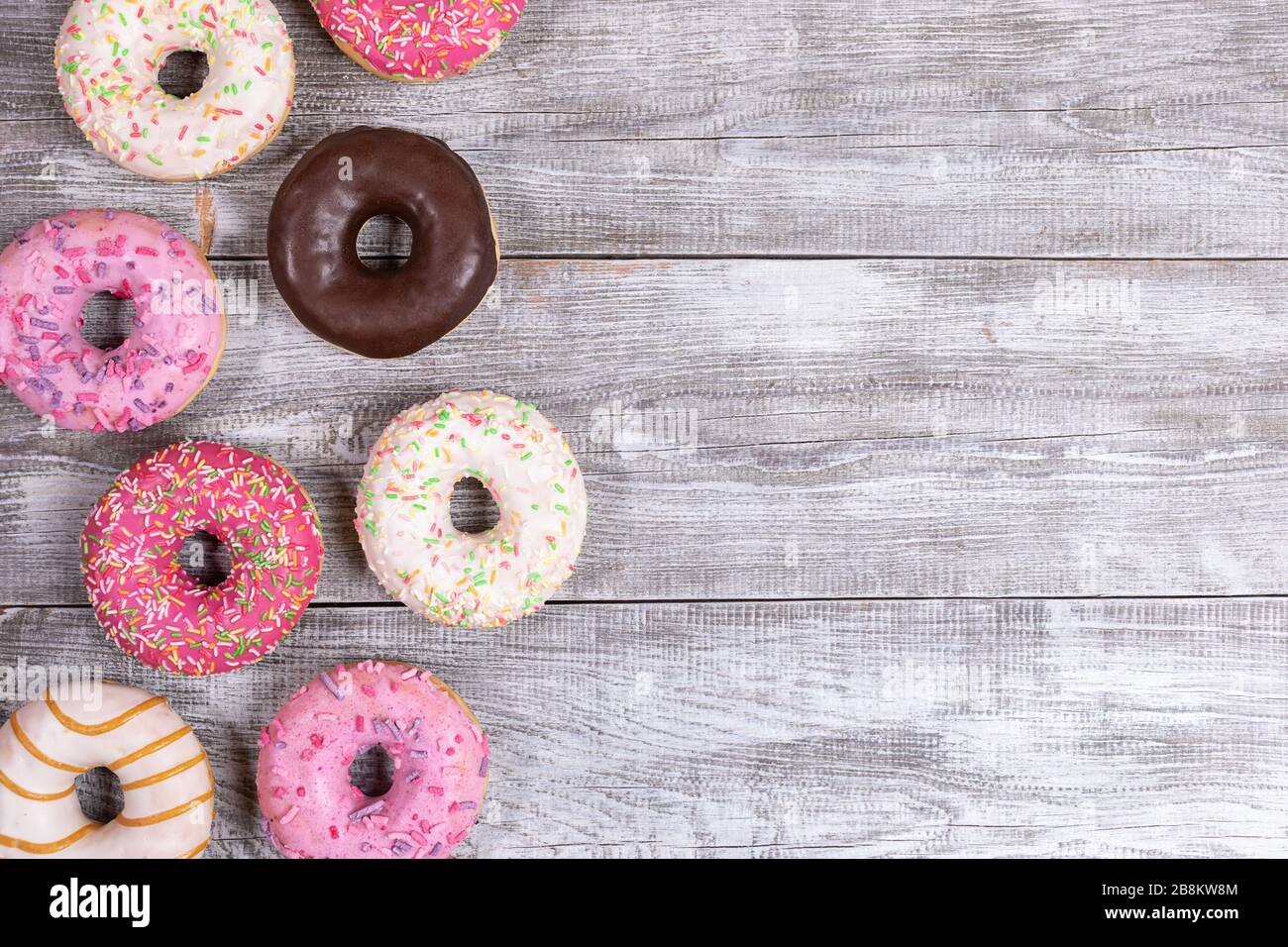Traditional doughnuts with multicolored glaze laid out on white painted ...