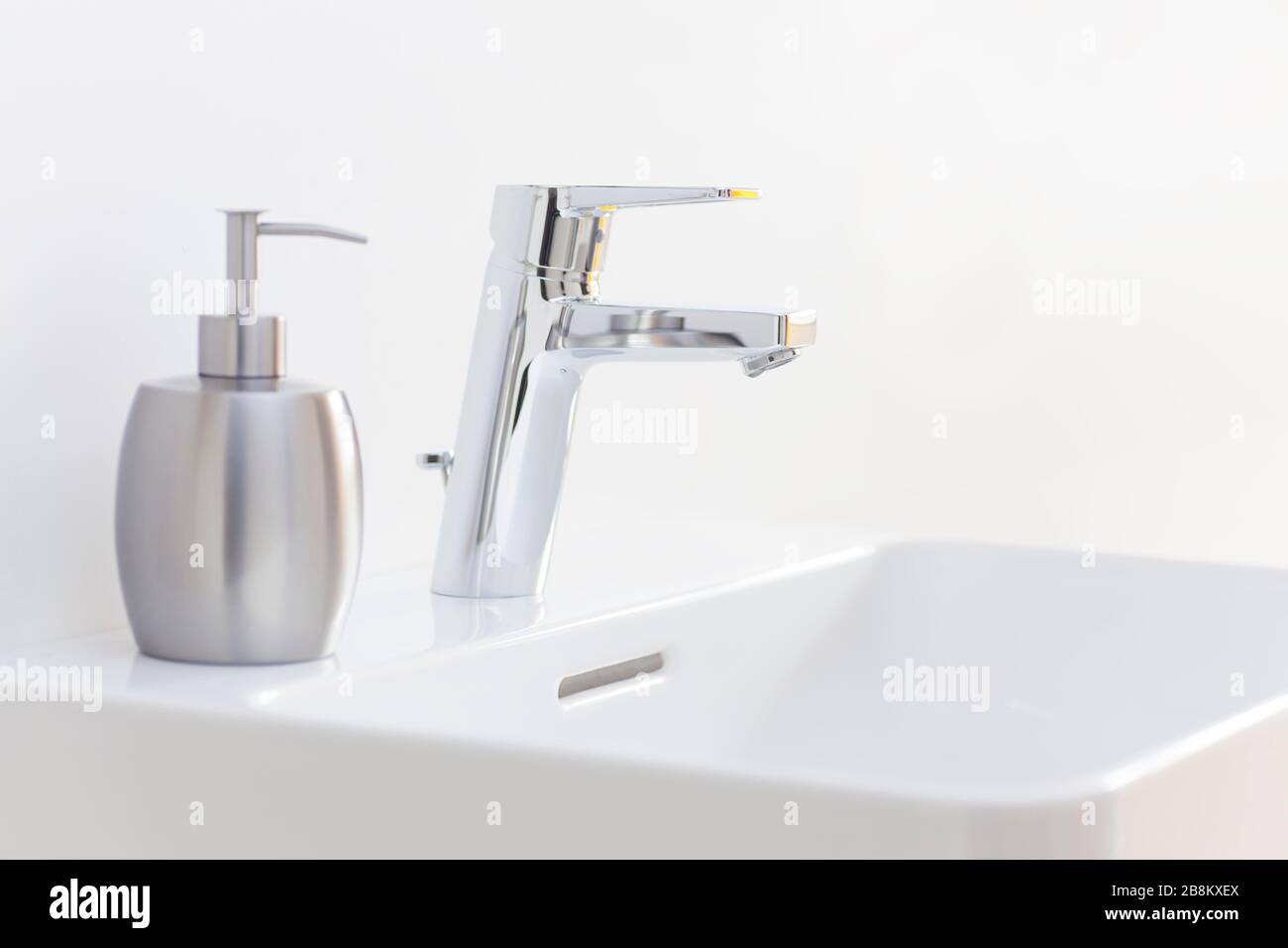 Faucet with tap and liqid soap in bright white bathroom - focus on the ...