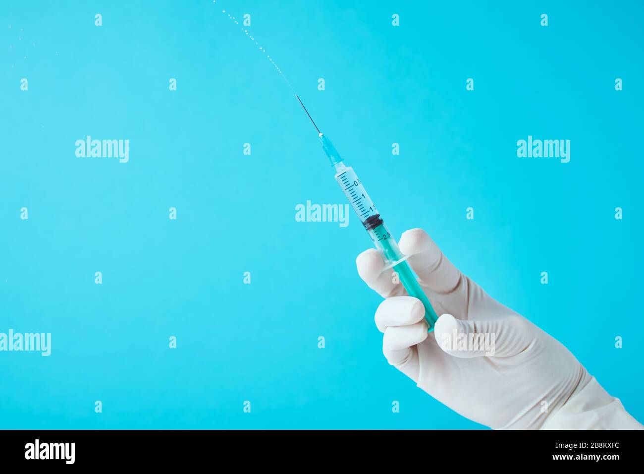 Hands in gloves hold an injection syringe against blue background ...