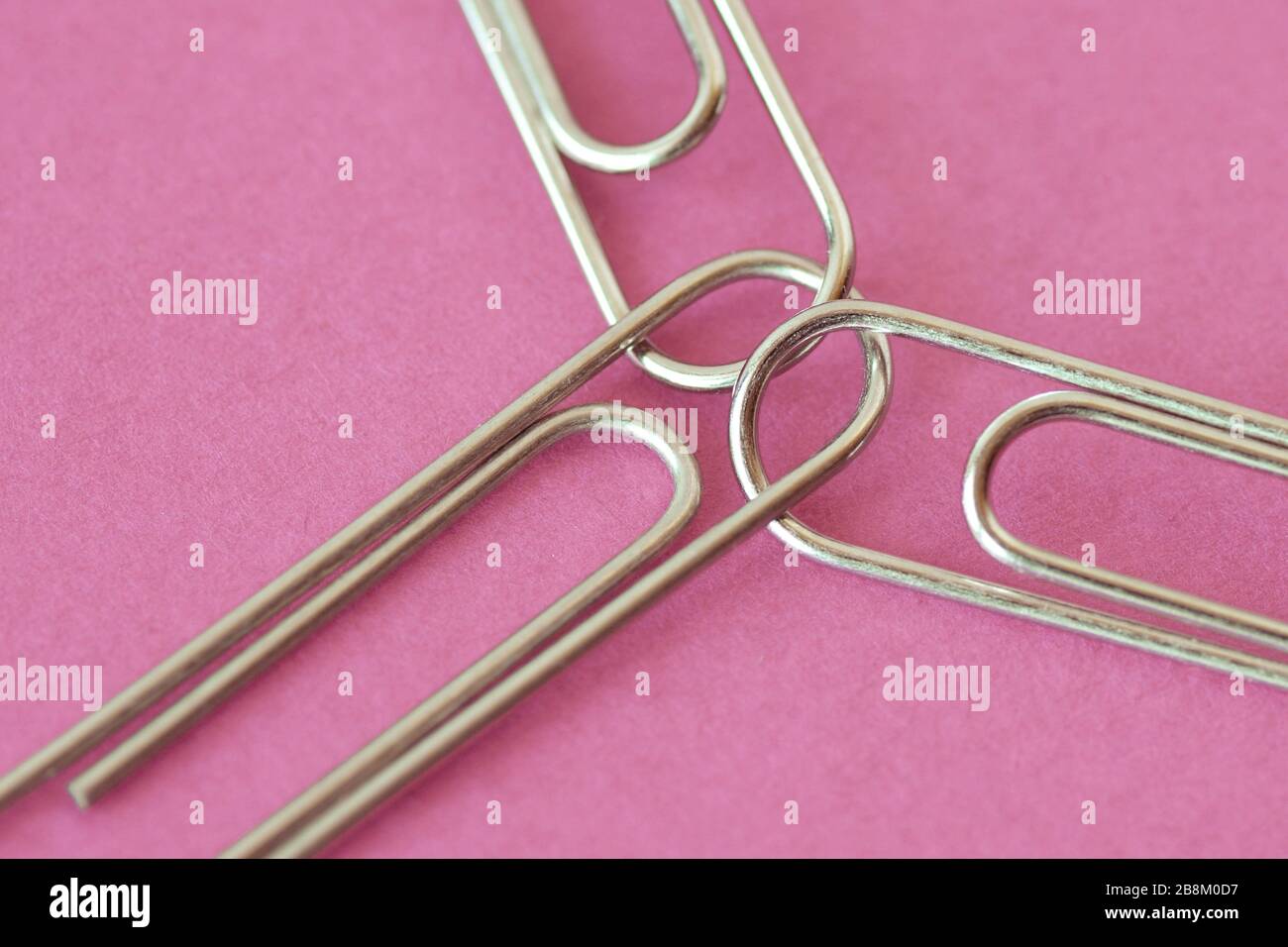 Three joined paper clips on pink background - Concept of unity and ...